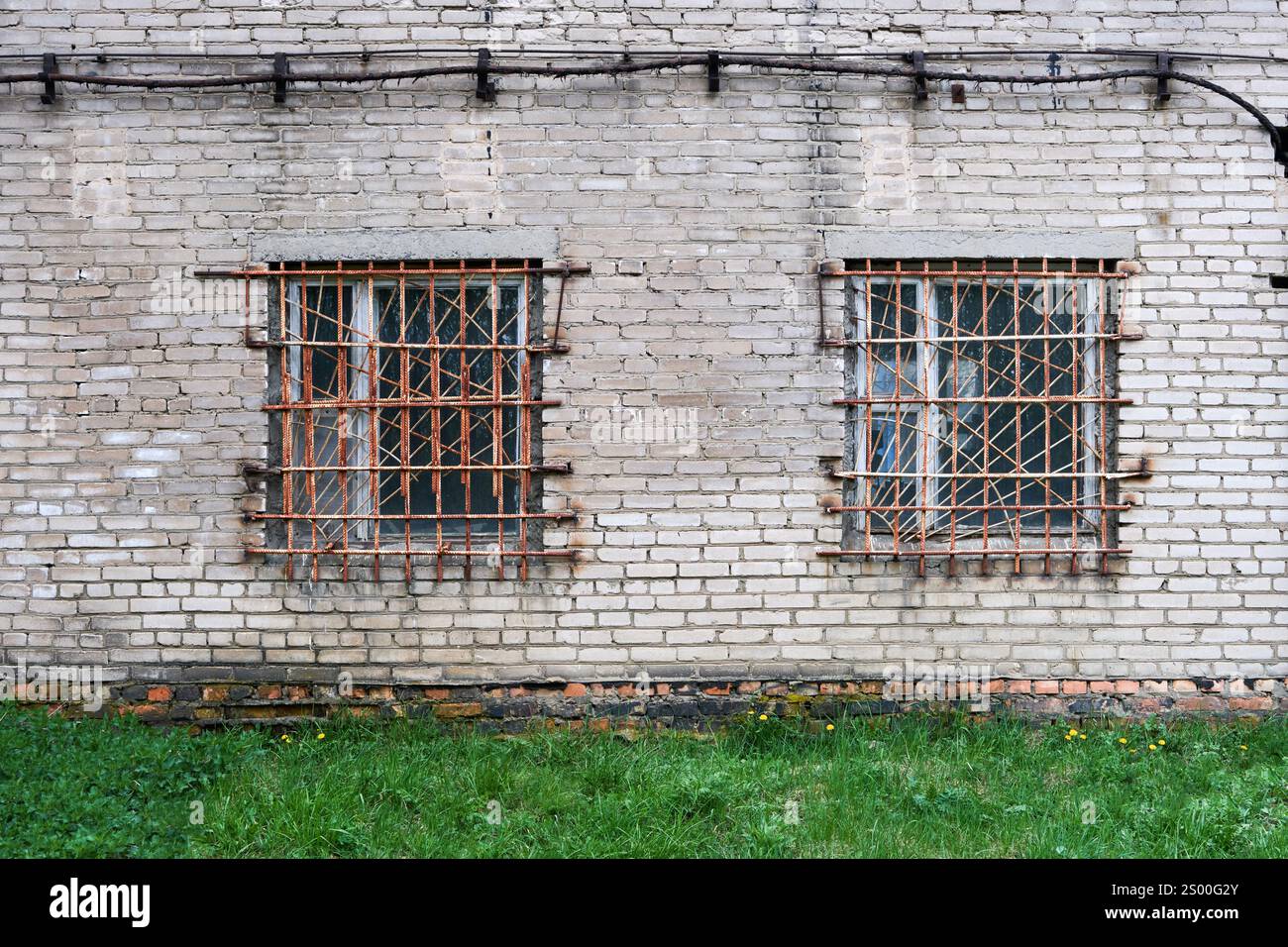 Two windows with metal bars on the old brick wall of an abandoned ...