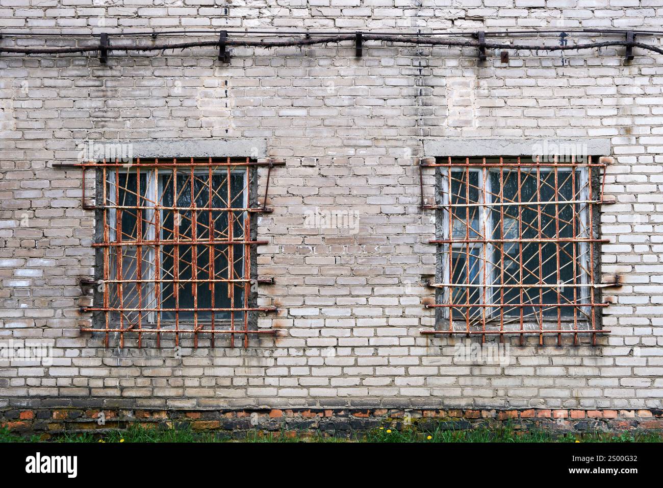 Two windows with metal bars on the old brick wall of an abandoned ...