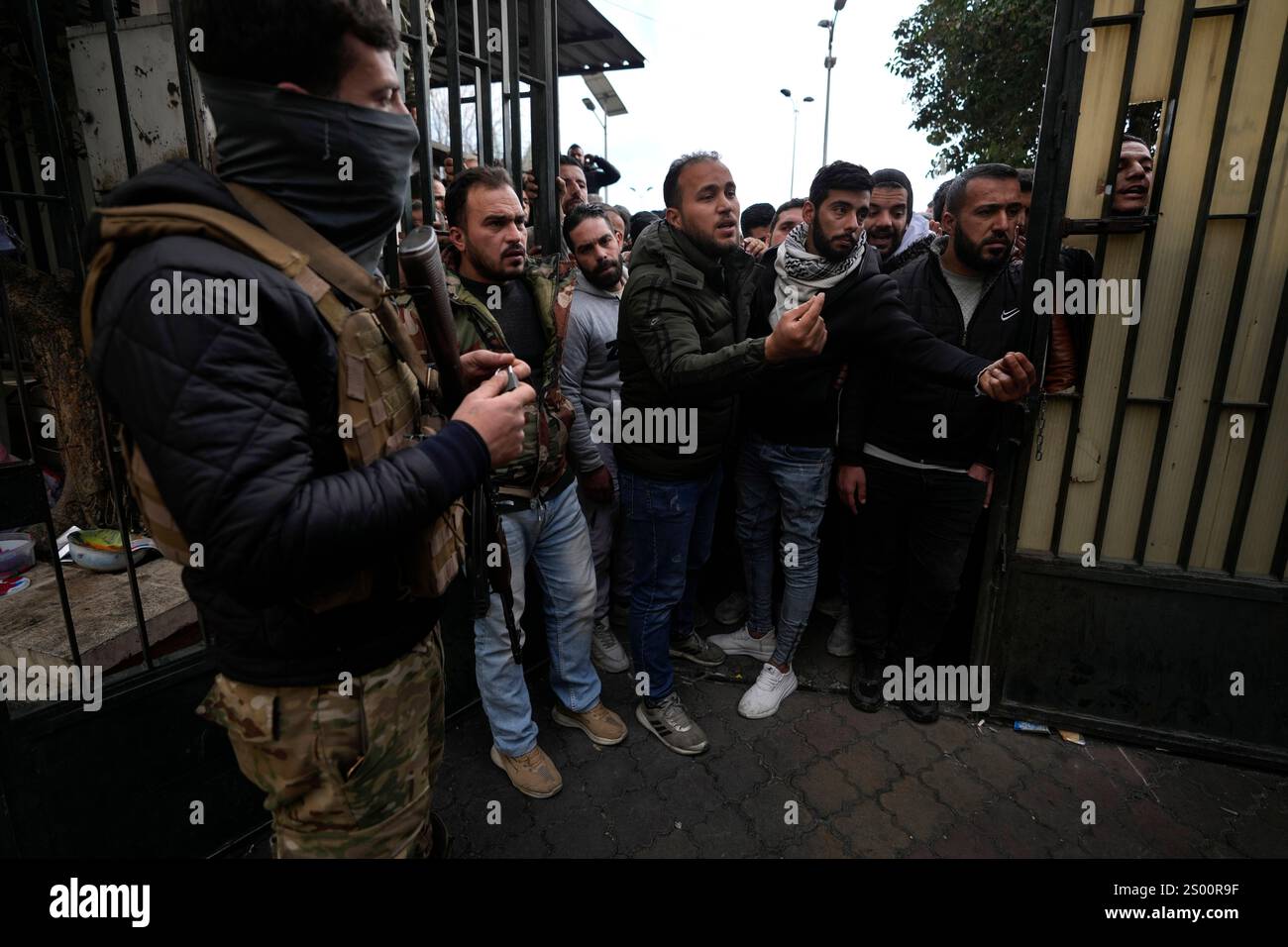 A Syrian fighter, left, stands guard as members of ousted Syrian ...