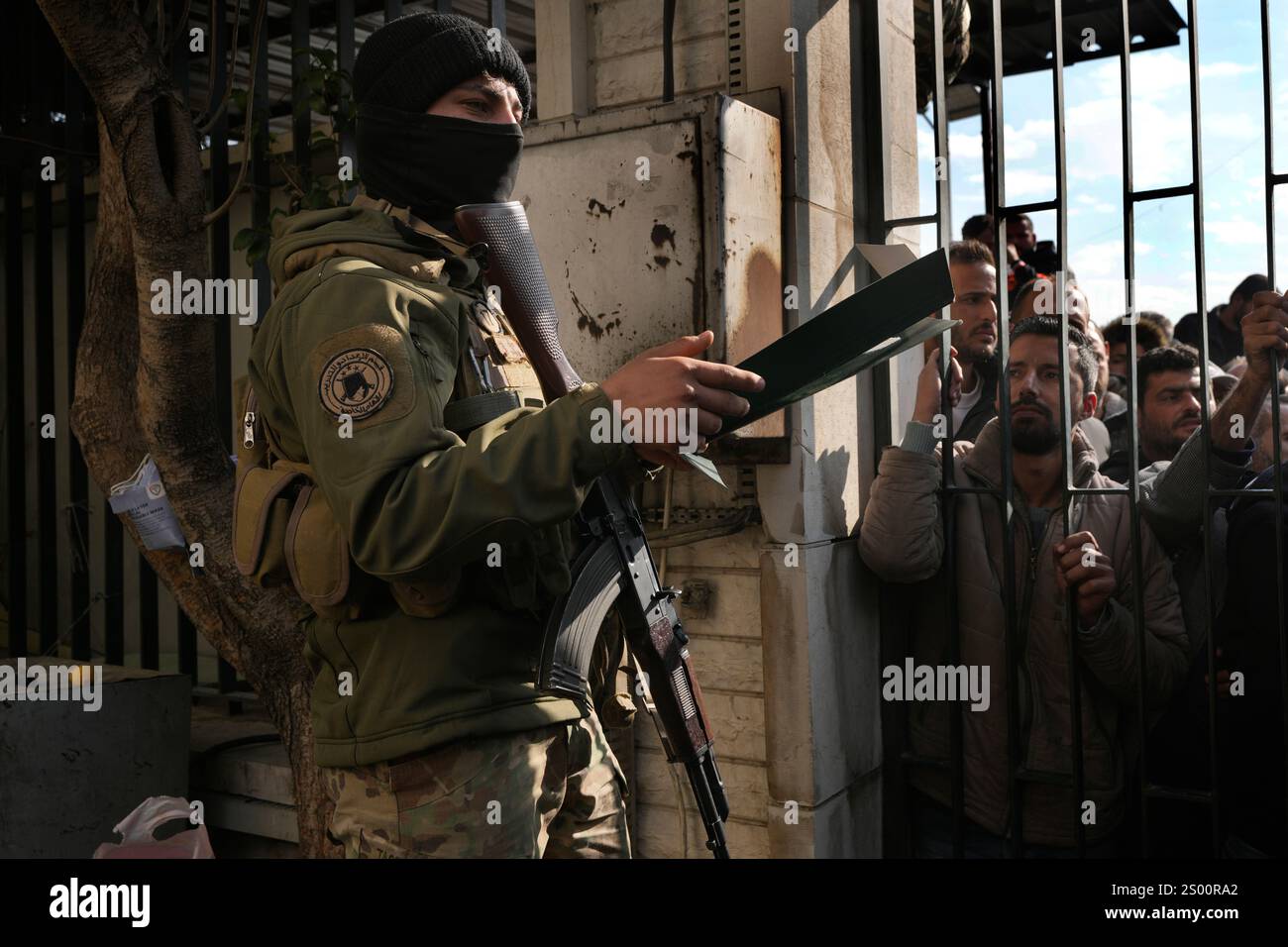 A Syrian fighter, left, stands guard as members of ousted Syrian ...