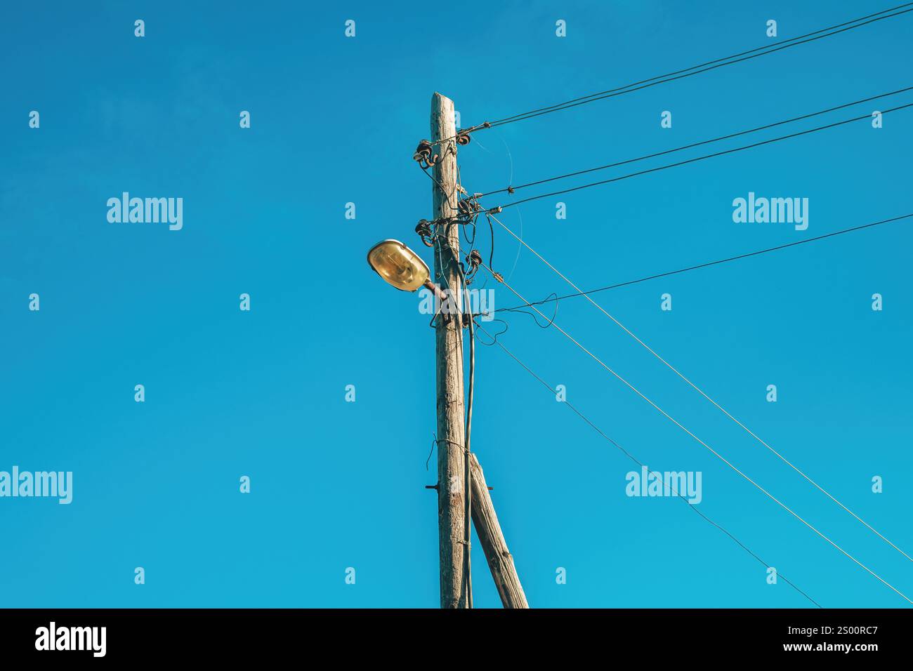 Old wooden lamp post with street light and electrical wires, selective ...
