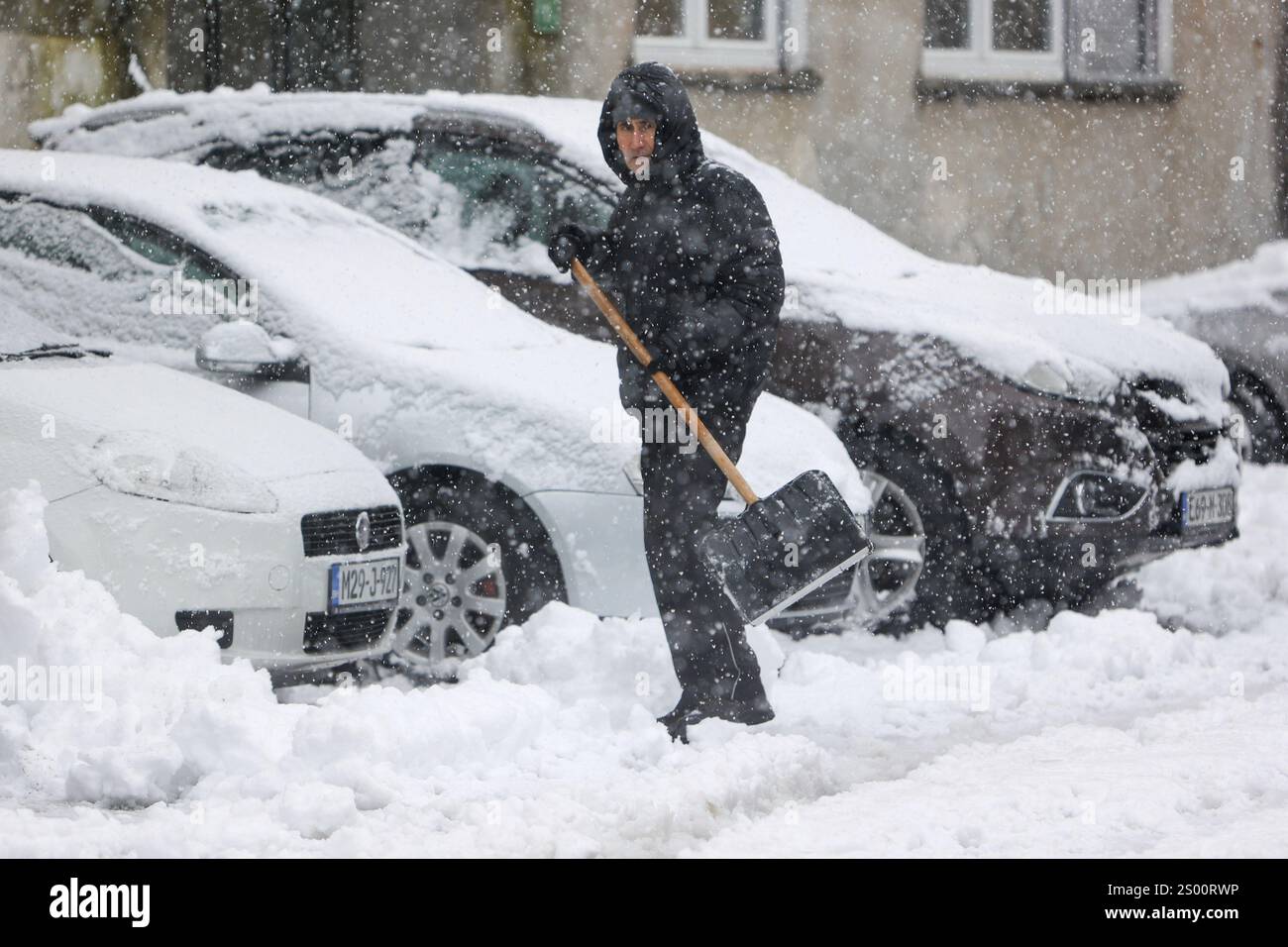 A man shovels snow from the street during heavy snowfall in Bihac ...