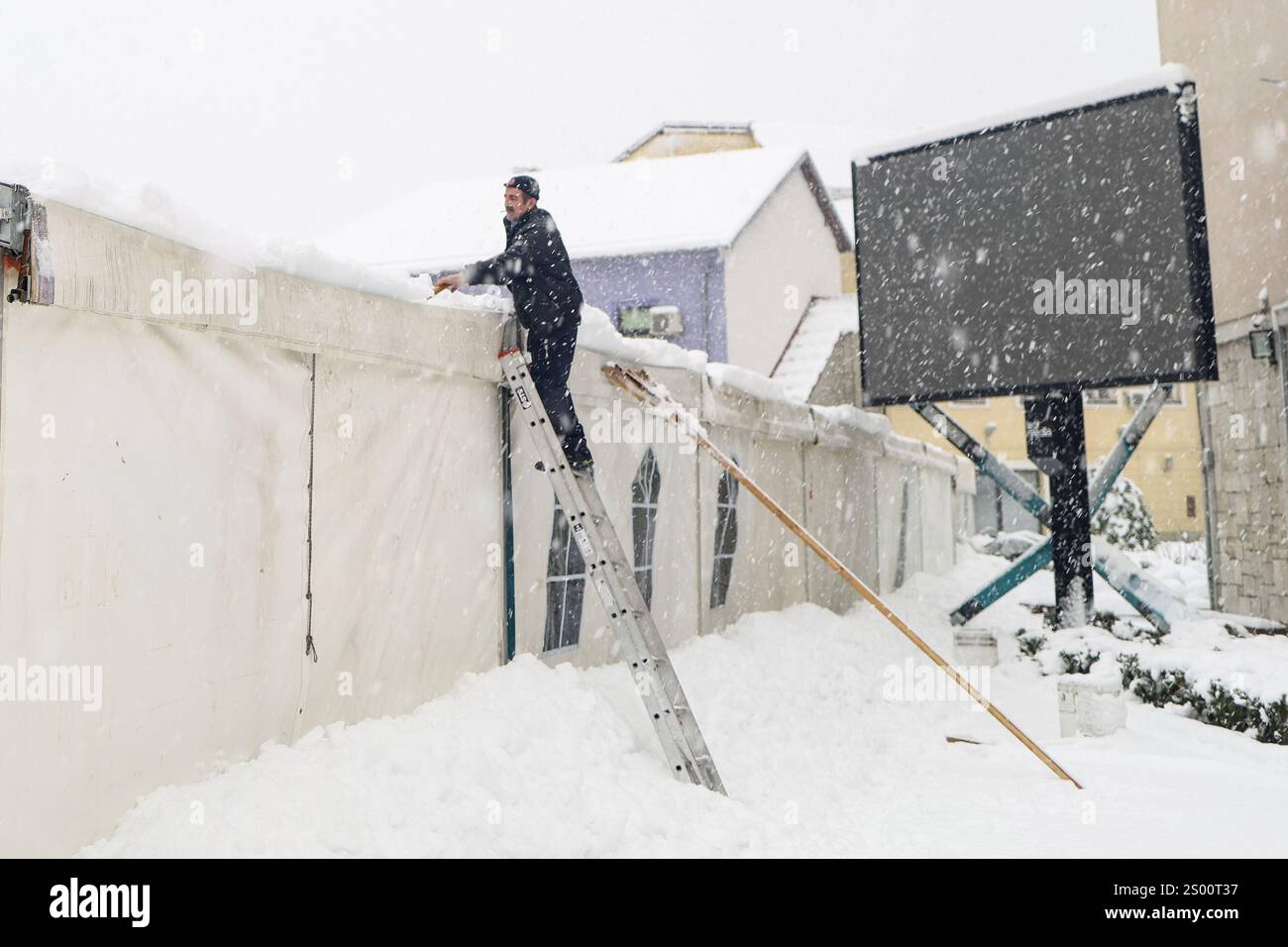 A man clears snow from a tent during heavy snowfall in Bihac, Bosnia ...