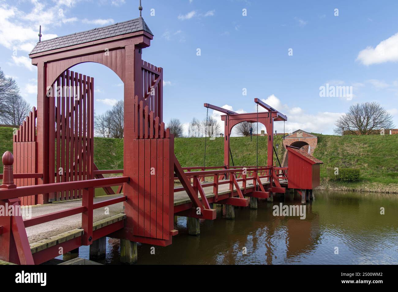 View of canal with bright red bridge and rampart around the village of ...