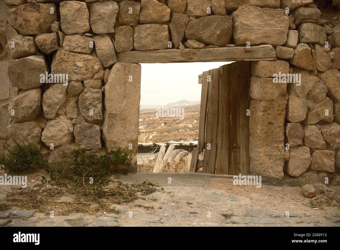 Ancient stone gate with a rustic wooden door featuring a rural view of ...