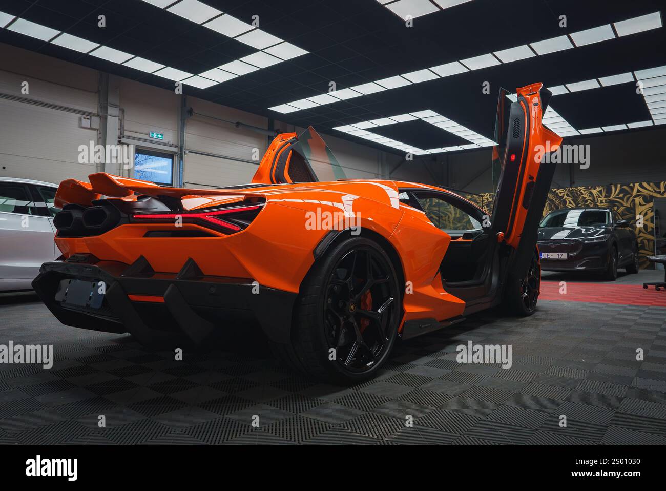 An orange Lamborghini Revuelto is displayed indoors with scissor doors ...