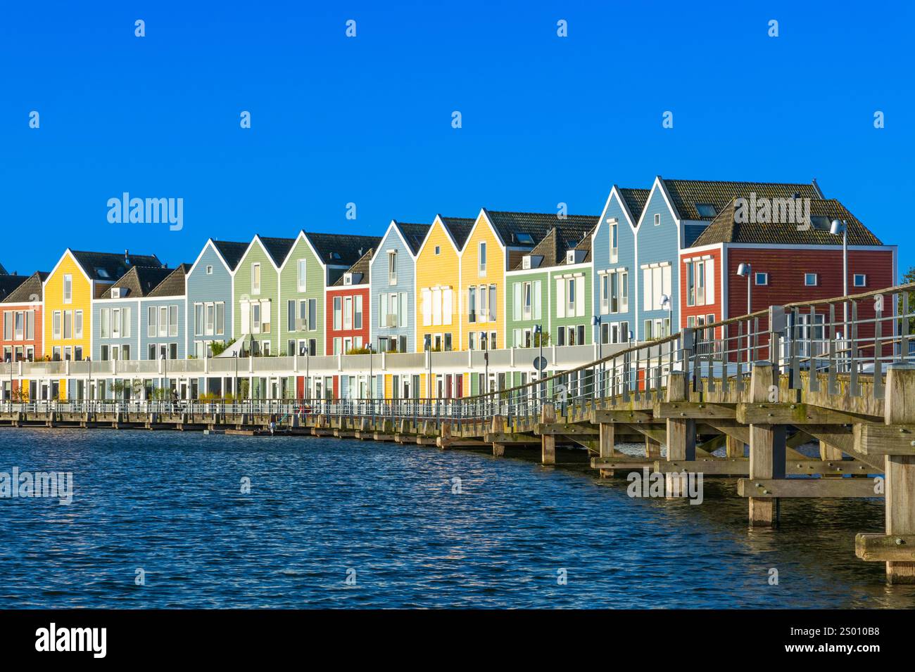 Row of colorful modern houses and bridge along water in a family ...