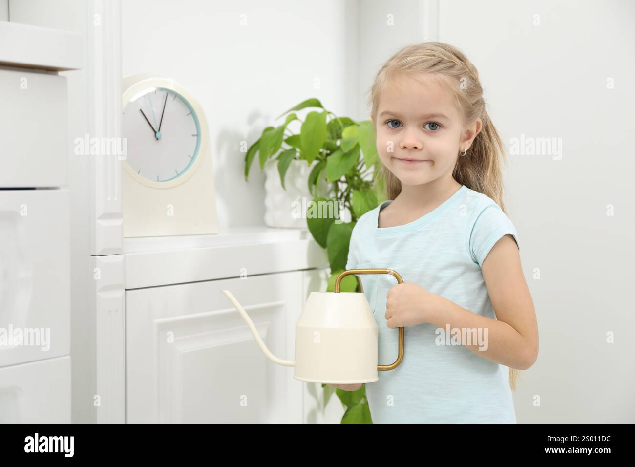 Little helper. Cute girl with watering can at home Stock Photo - Alamy