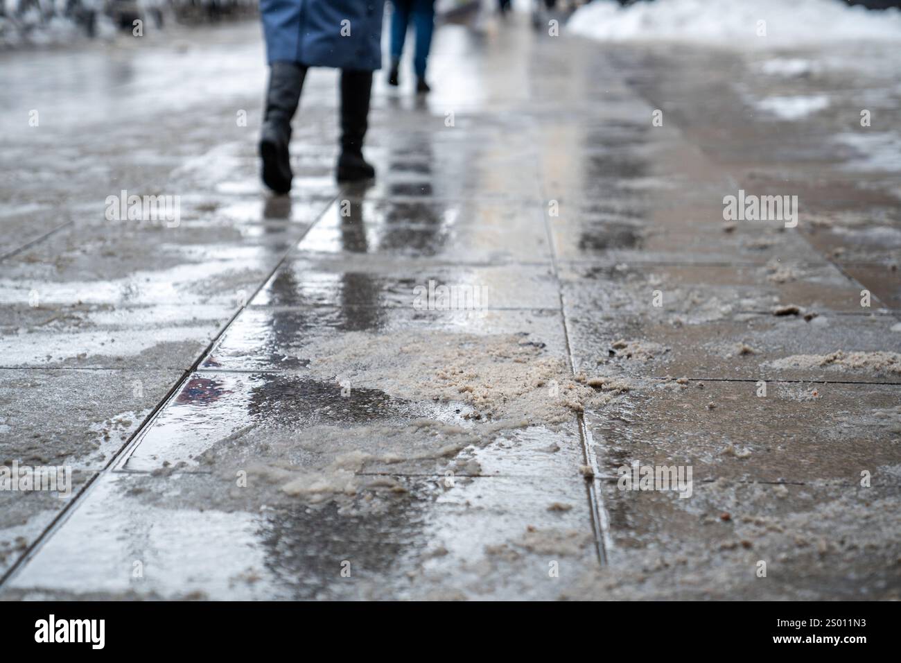Anti-icing chemicals. Woman walking on the street treated with ...
