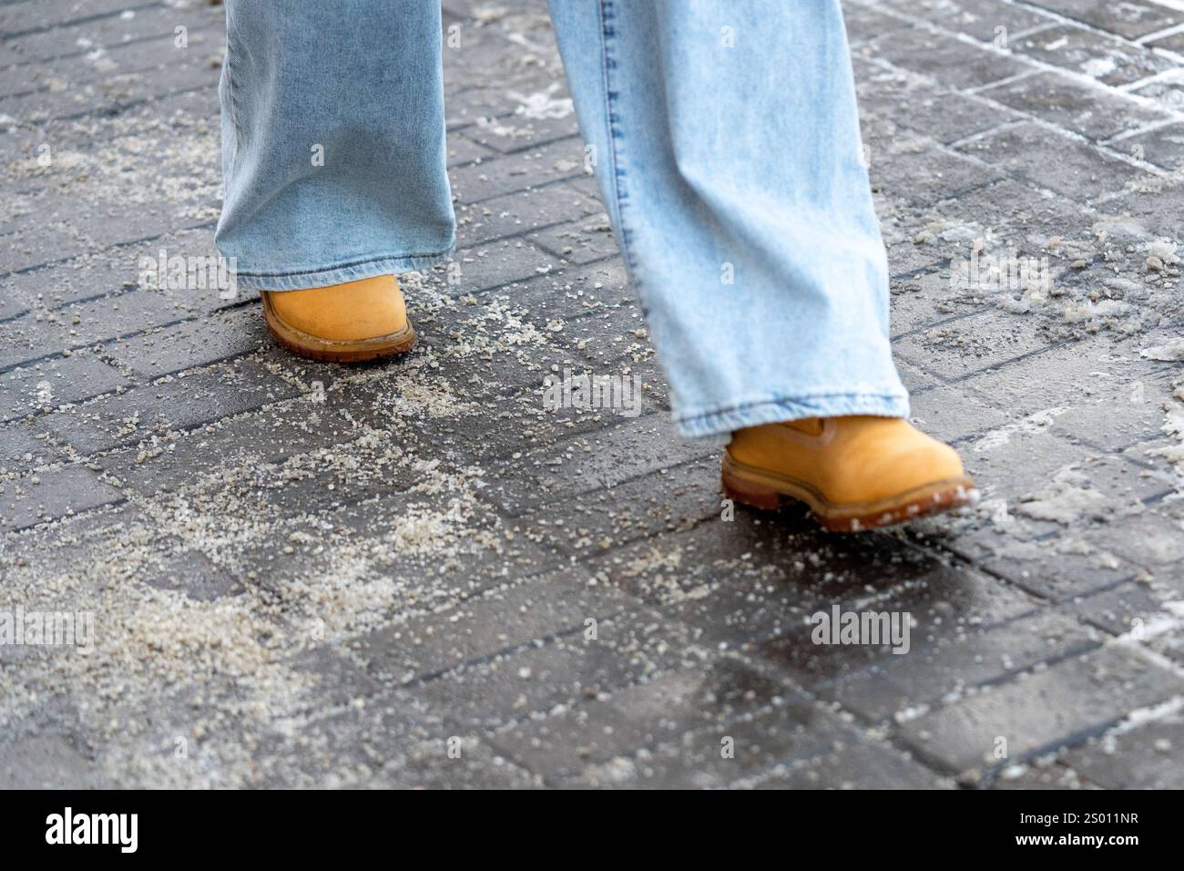 Anti-icing chemicals. Man walking on the street treated with technical ...