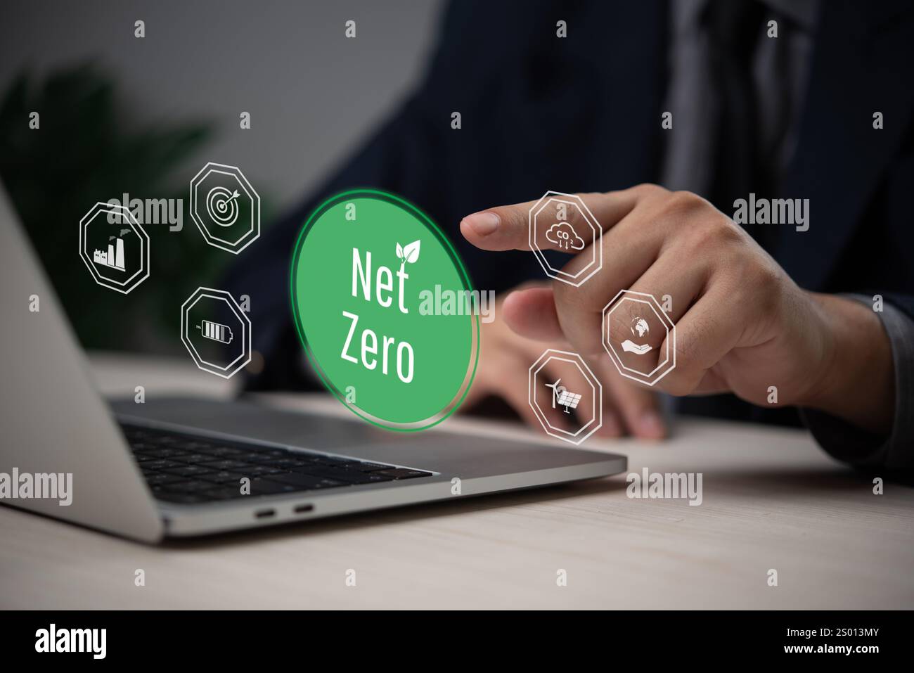 Businessman pointing to a glowing net zero symbol on a laptop ...