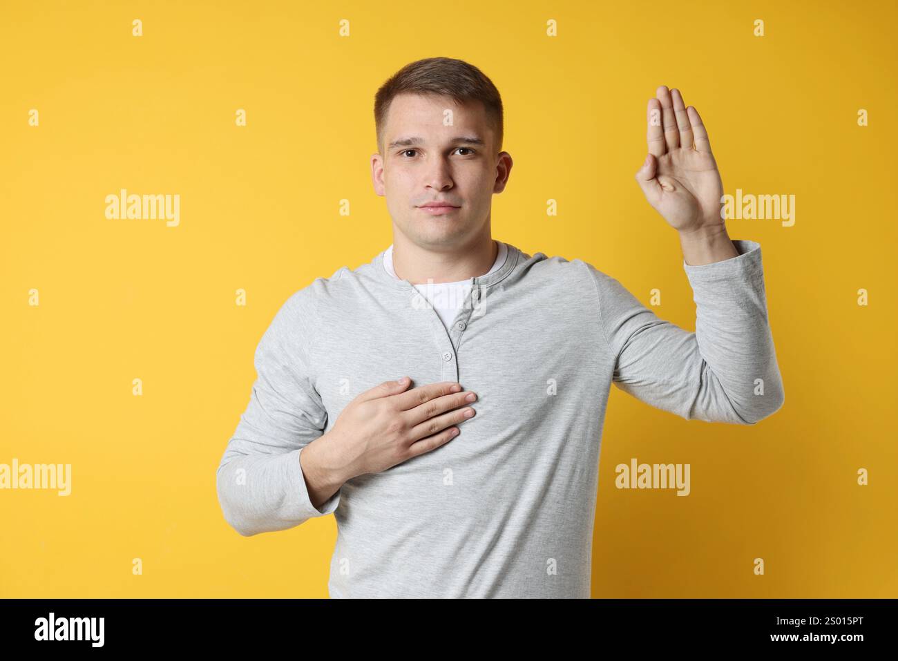 Man making promise with raised hand on orange background. Oath gesture ...