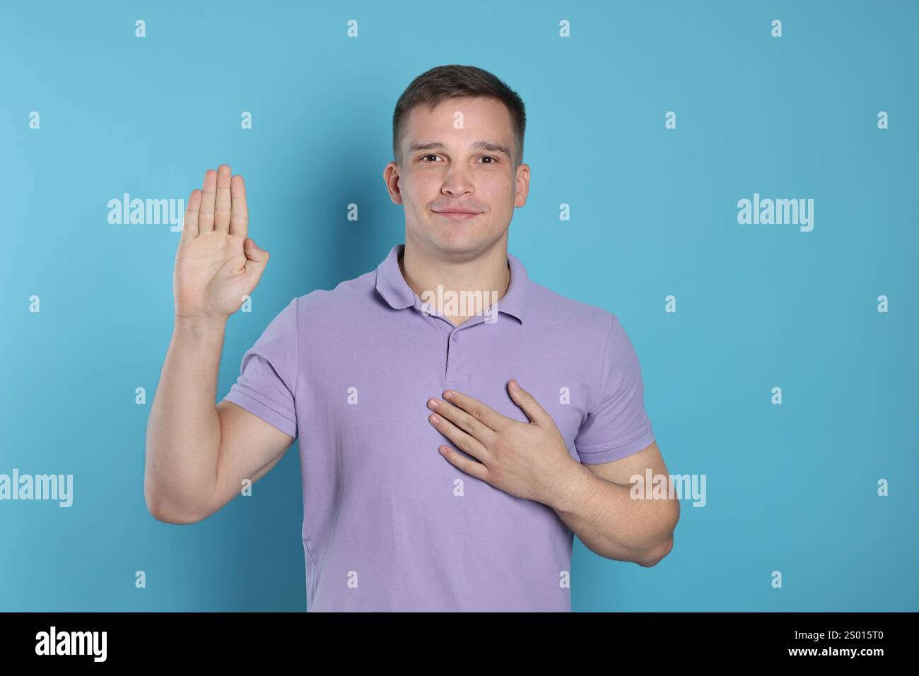 Man making promise with raised hand on light blue background. Oath ...