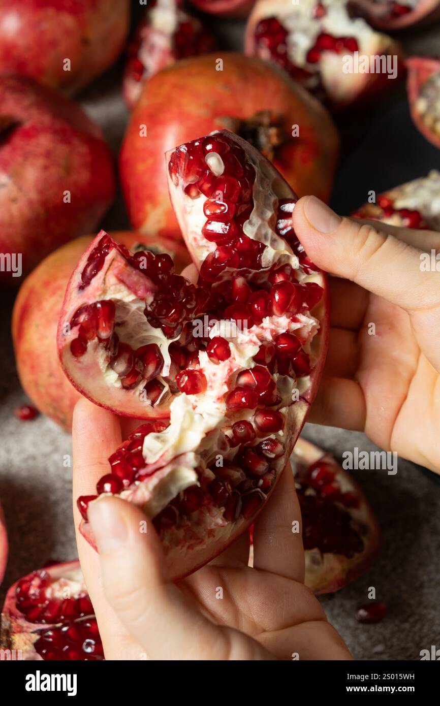 Hands open the pomegranate, separation into parts, pomegranates grains ...