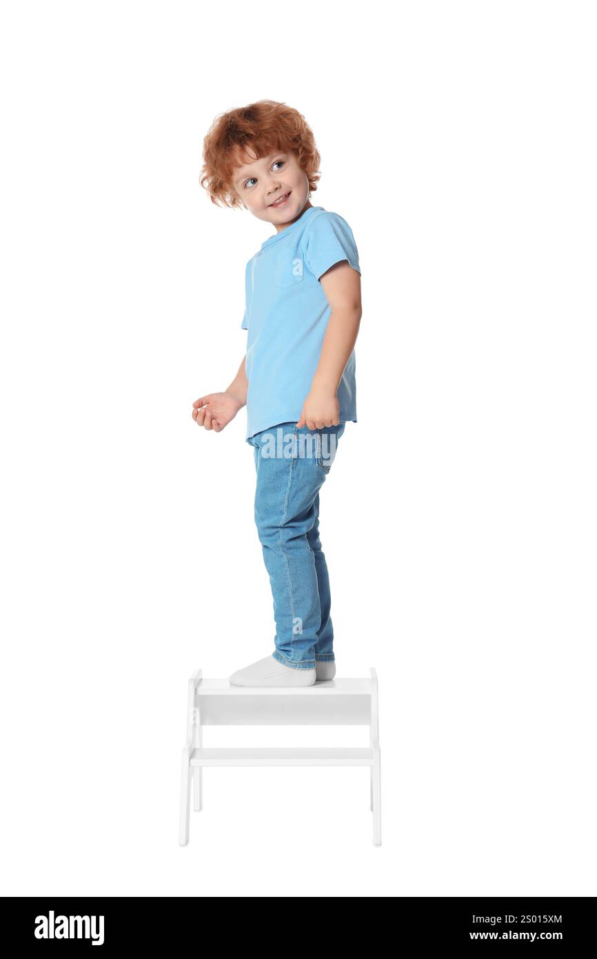 Little boy standing on step stool against white background Stock Photo ...