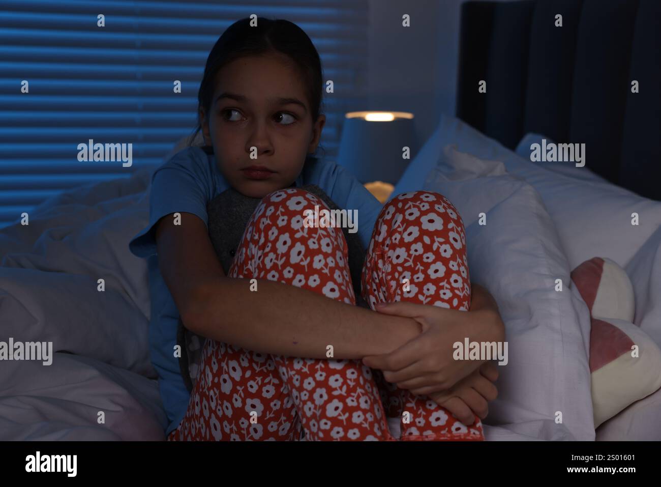 Fearful girl sitting on bed at night Stock Photo - Alamy
