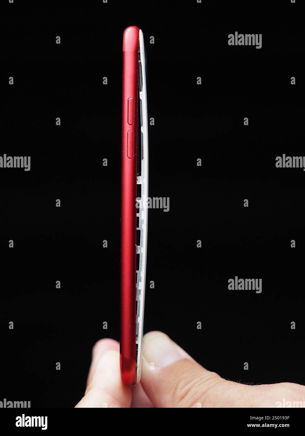 xA hand displays a slim red smartphone from the side with swollen ...
