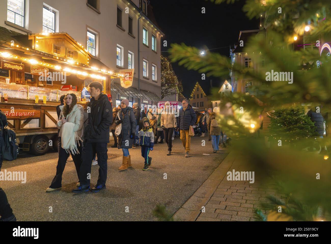 People stroll through an illuminated Christmas market, surrounded by ...