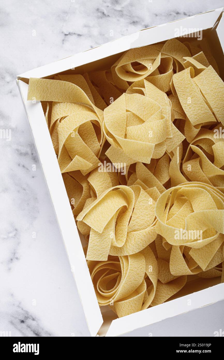 Raw pappardelle pasta, pasta nests, in a paper box, top view, no people ...