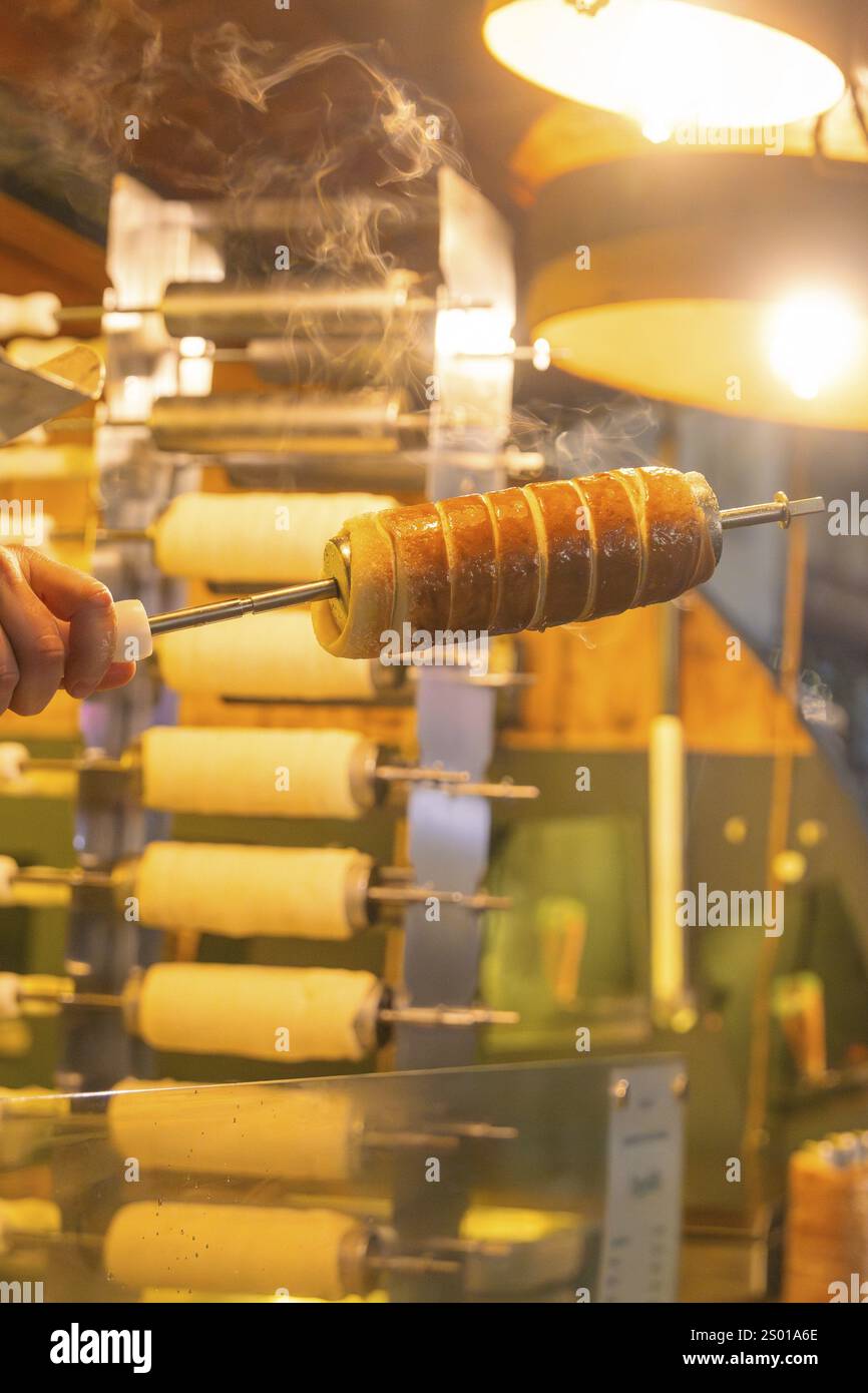 A golden brown Baumstriezel roll steams in warm light at a Christmas ...