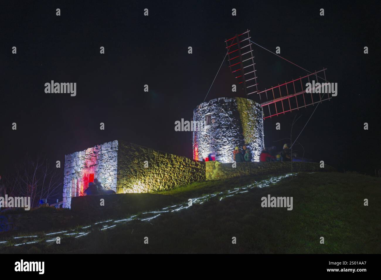 Historic windmill at night, illuminated with red and blue modern lights ...