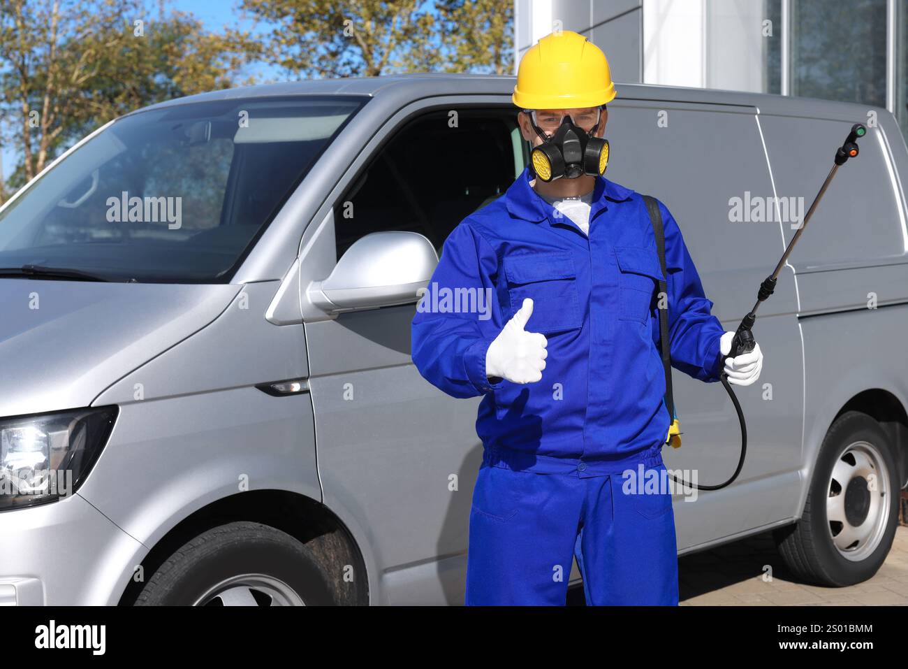 Pest control worker with spray tank showing thumbs up outdoors Stock ...