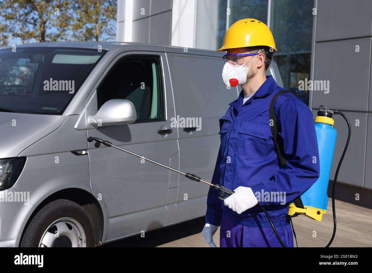 Pest control worker with spray tank near gray minibus outdoors Stock ...