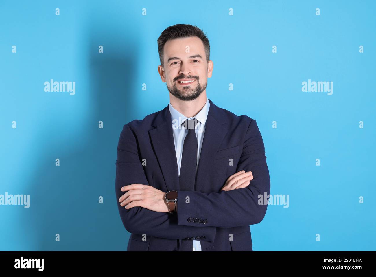 Portrait of smiling banker with crossed arms on light blue background ...
