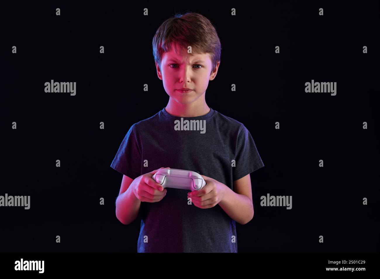 Little boy playing video game with controller on black background Stock ...