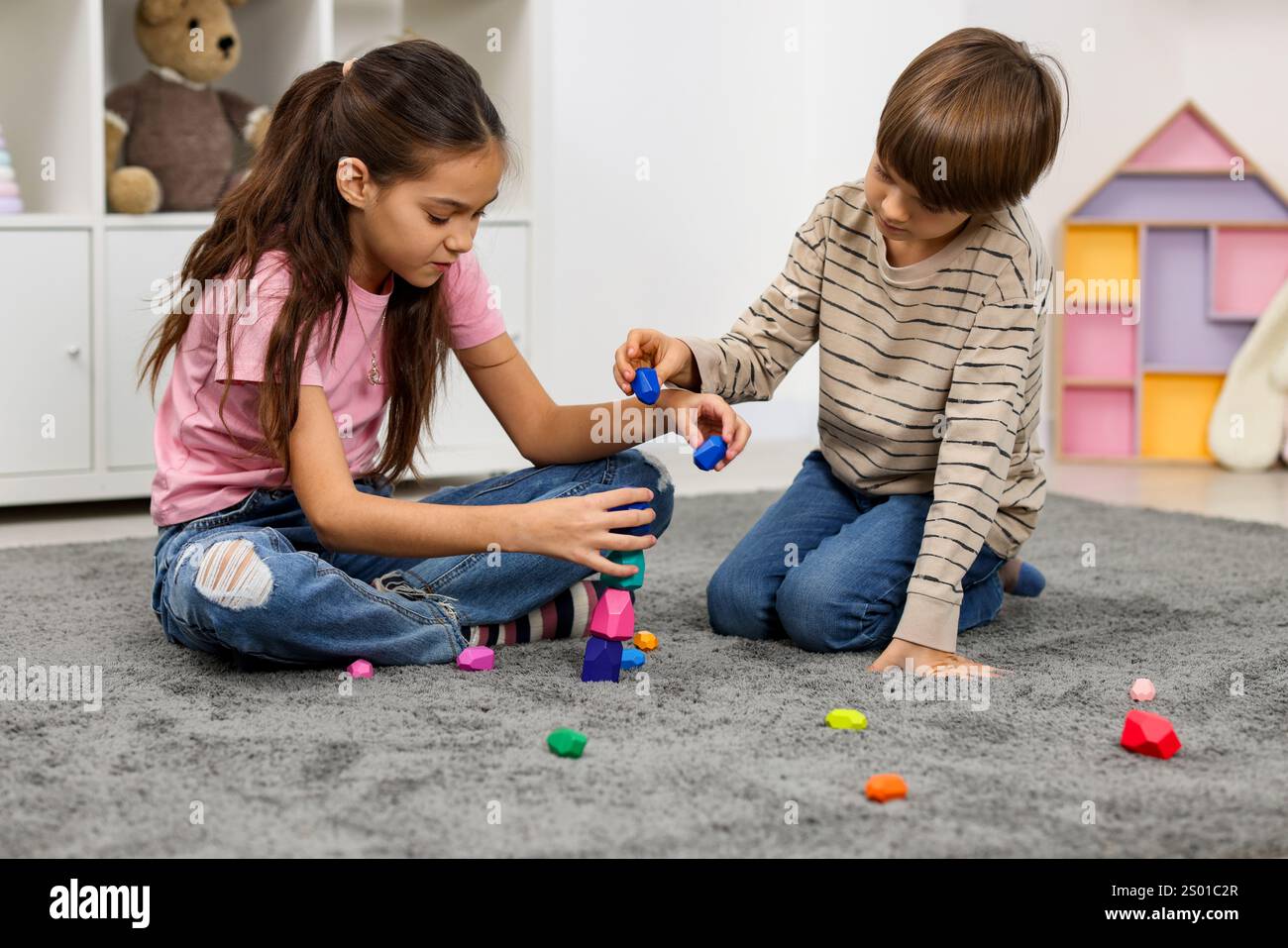 Children playing with balancing stones on floor indoors Stock Photo - Alamy