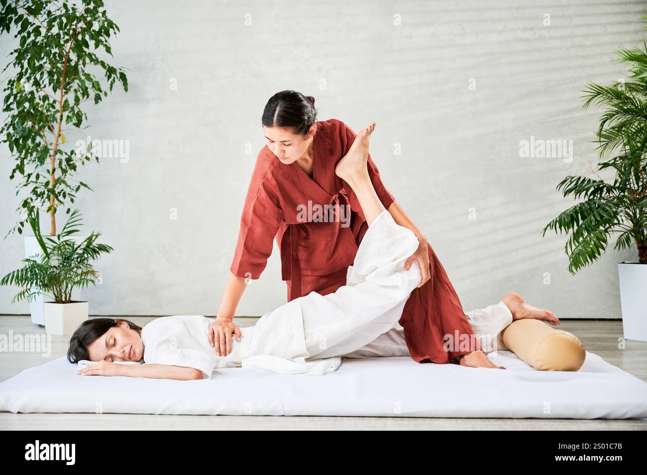 Masseuse making thai yoga massage. Woman therapist doing traditional ...