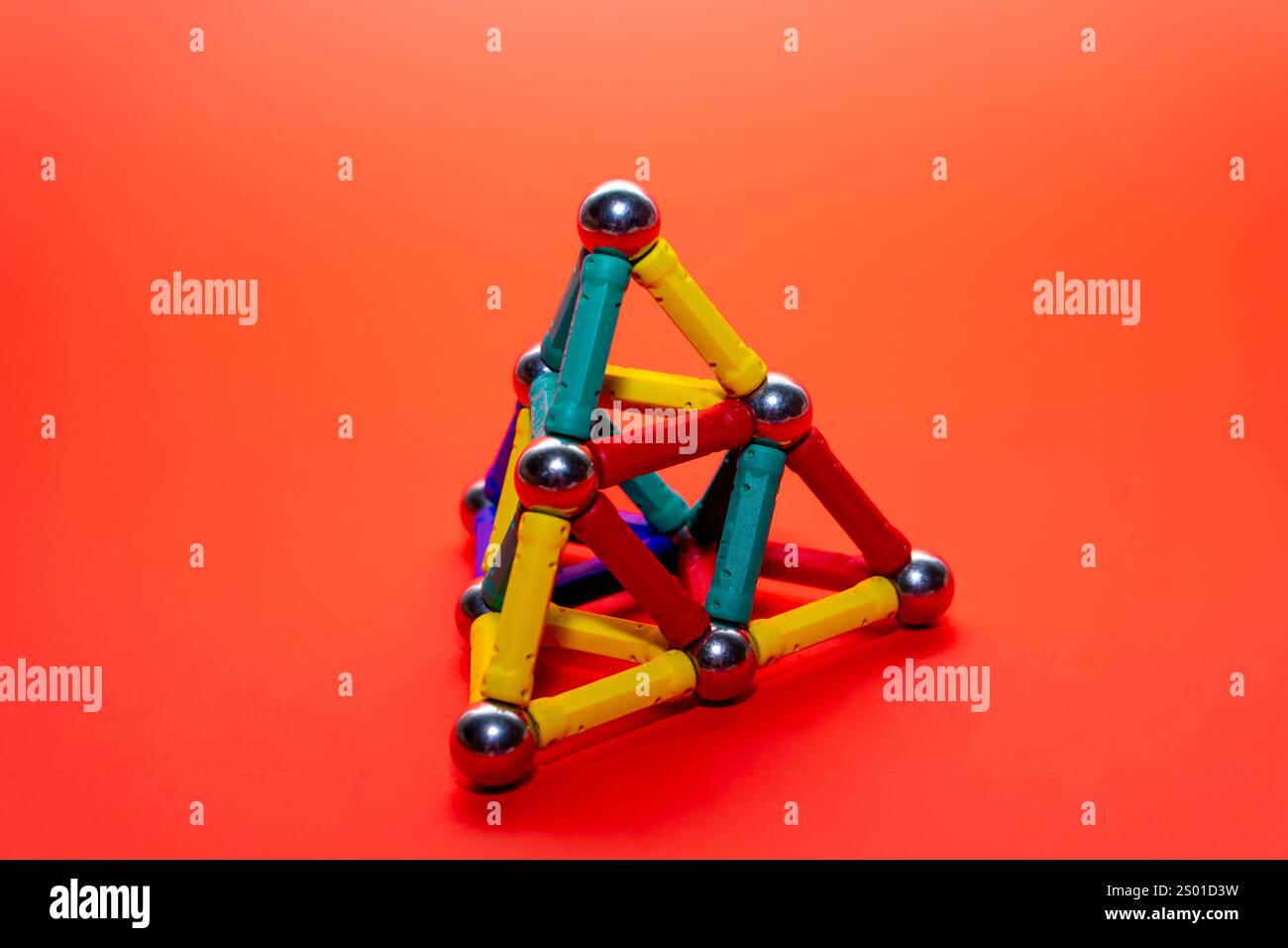 A small pyramid made of colorful sticks and metal balls sits on a ...