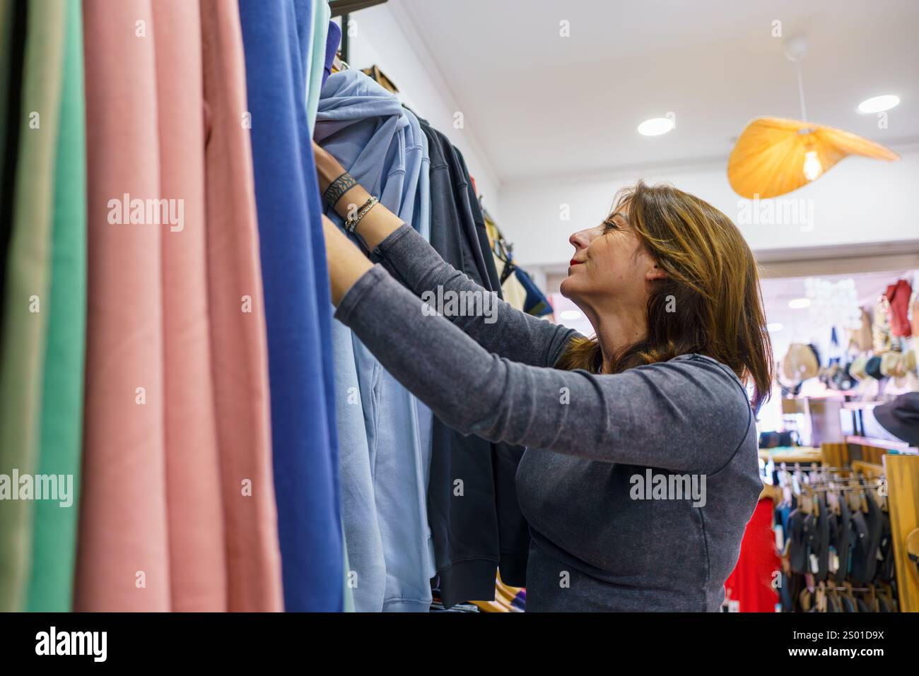 Female customer browsing through colorful clothes on hangers in a ...