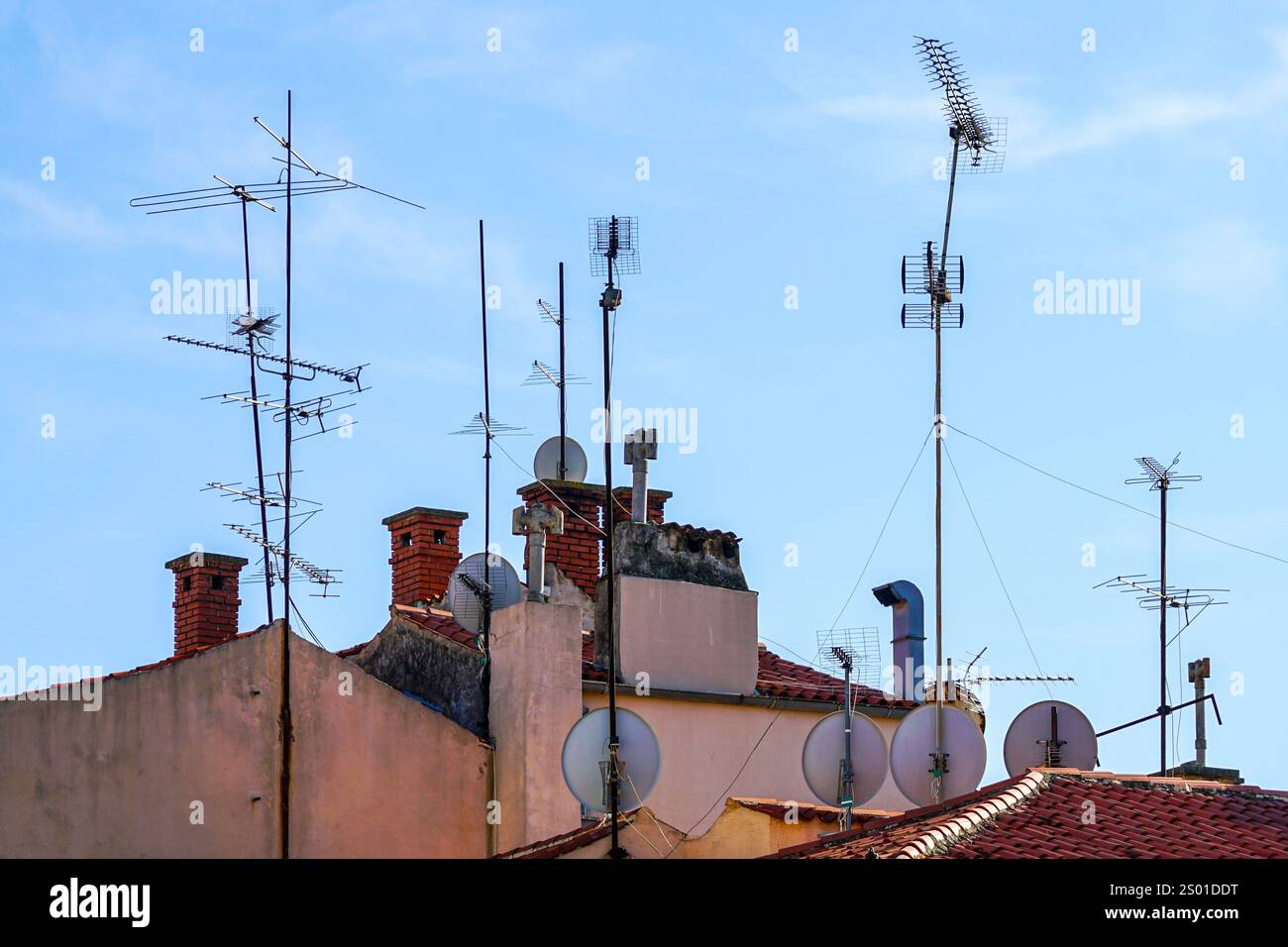 Many aerial digital television reception antennas and satellite dishes installed on the rooftop ...