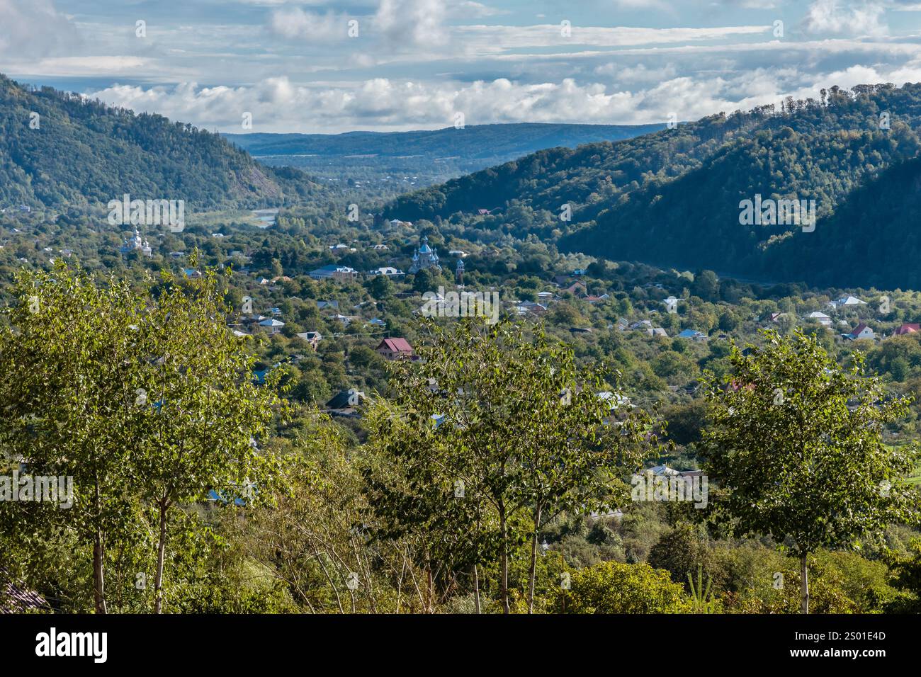 A beautiful mountain view with a small town in the distance. The trees ...