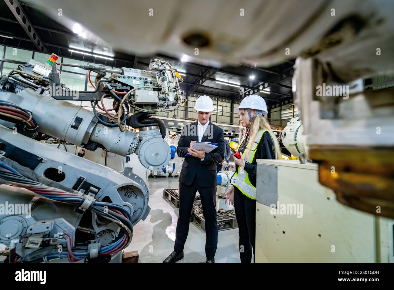 Two professionals evaluate a robotic system in an industrial setting ...