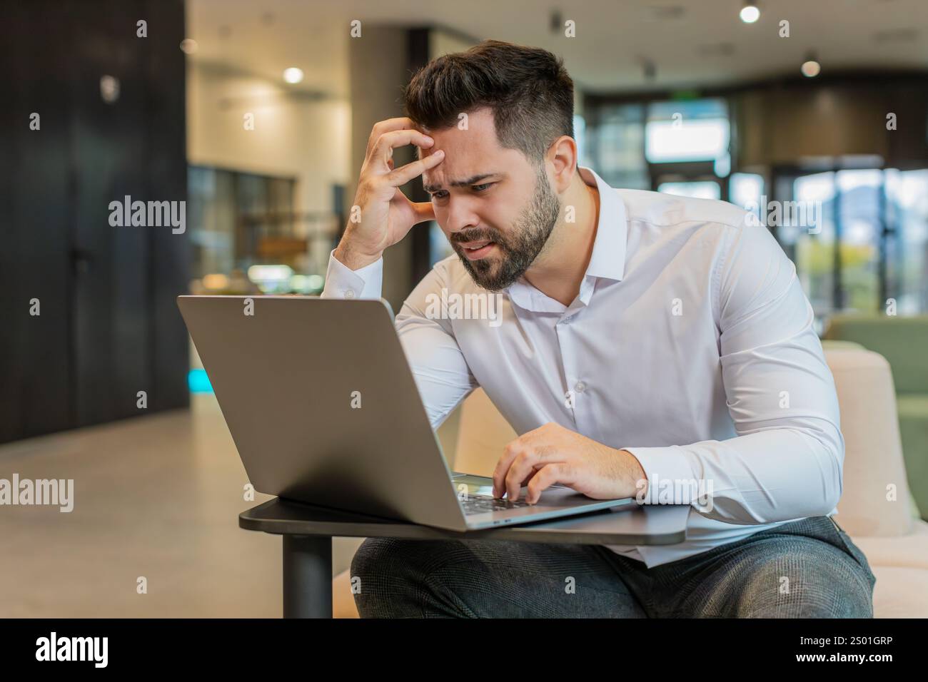 Sad young Caucasian businessman using laptop typing browsing, loses ...