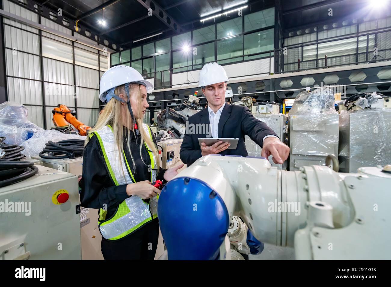 Two engineers discuss a robotics project while inspecting machinery in ...