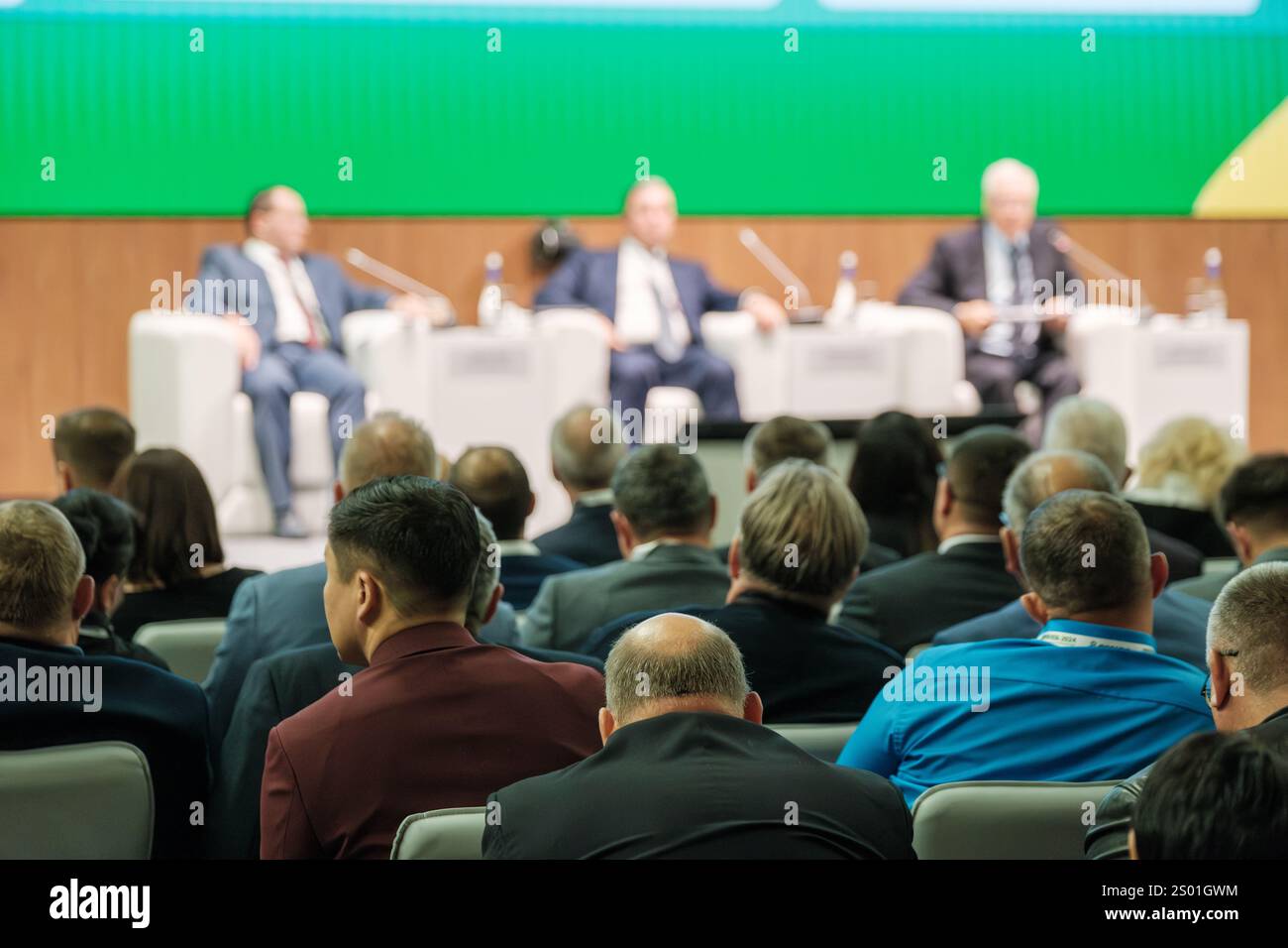 Focused attendees sit in auditorium watching corporate conference panel ...