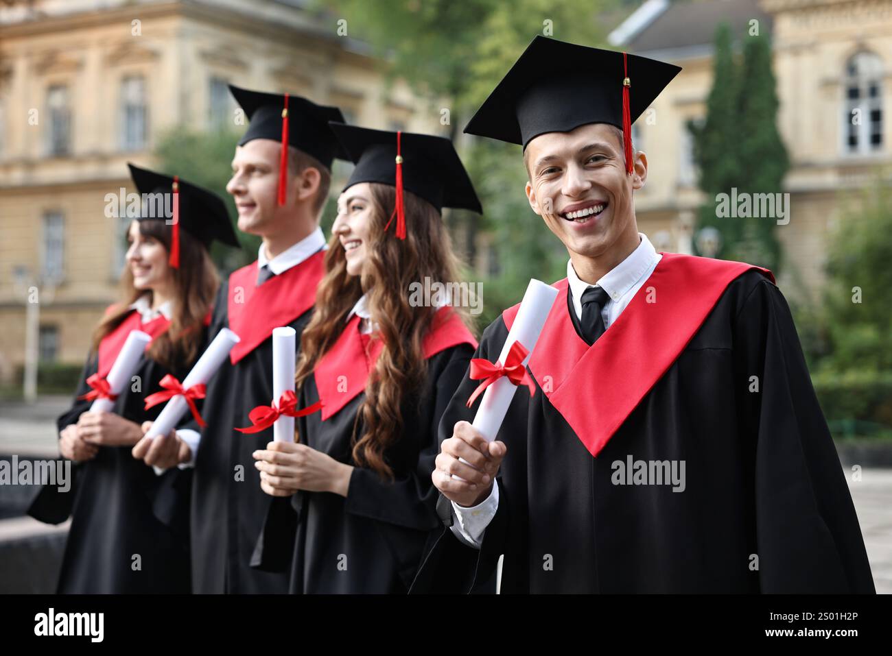 Happy students with diplomas after graduation ceremony outdoors ...