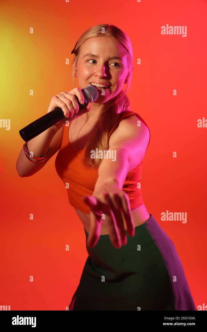 Talented singer performing on red background with yellow light Stock ...