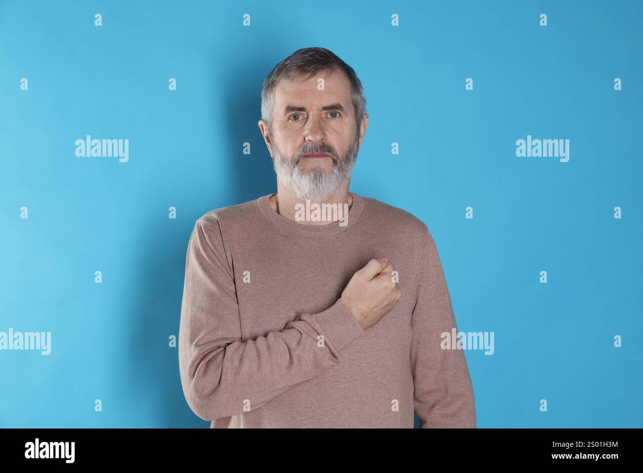 Mature man making promise on light blue background. Oath gesture Stock ...