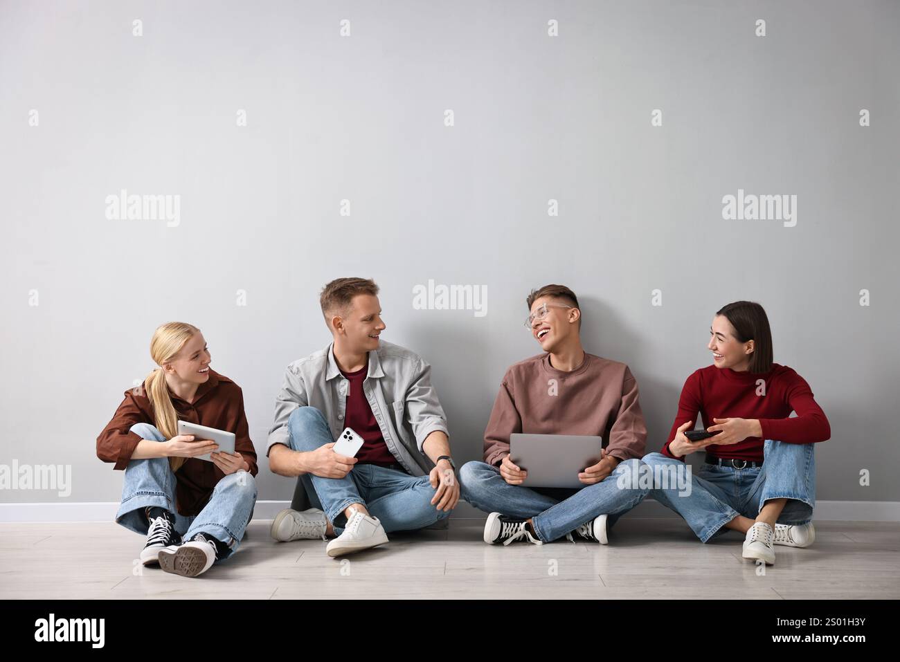 Group of people using different gadgets near light grey wall indoors ...
