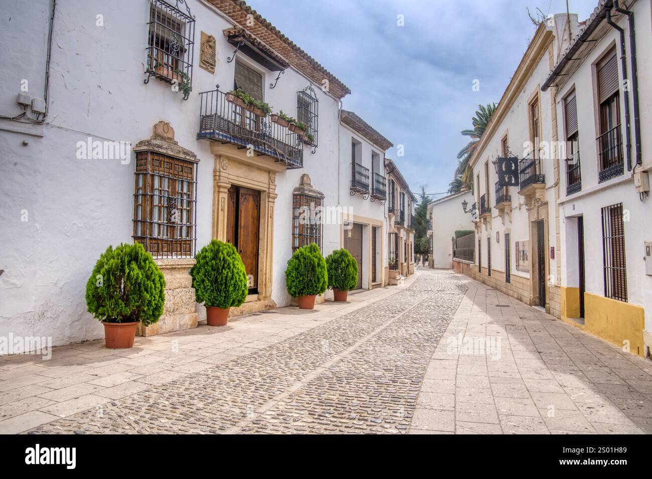 Old buildings line the cobblestone street in the village of Ronda ...