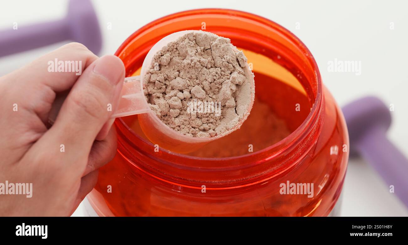 A man holding a scoop of soy protein isolate powder with chocolate in ...