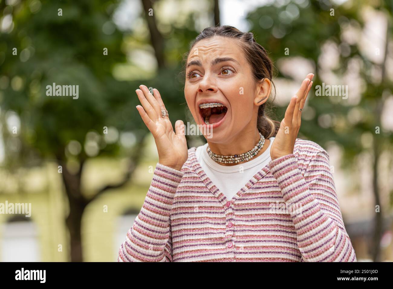 Irritated angry Caucasian young woman with braces on teeth screams from ...