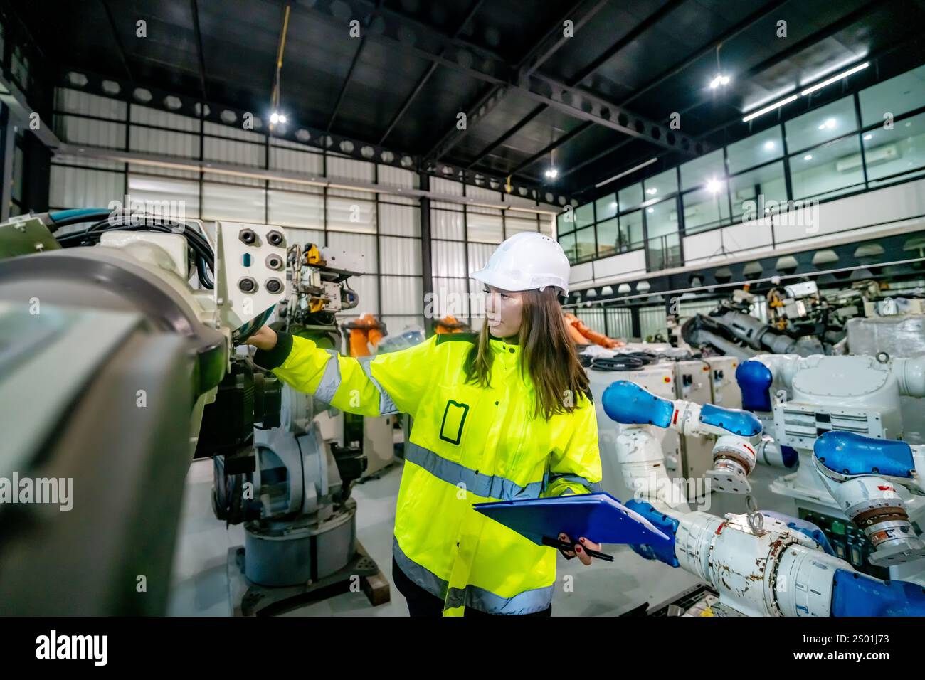 A worker wearing a safety helmet and bright yellow jacket examines ...