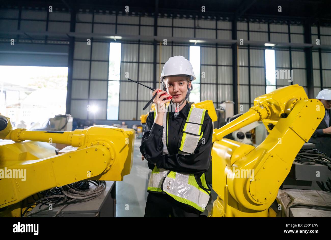 A female engineer stands confidently in an industrial facility ...