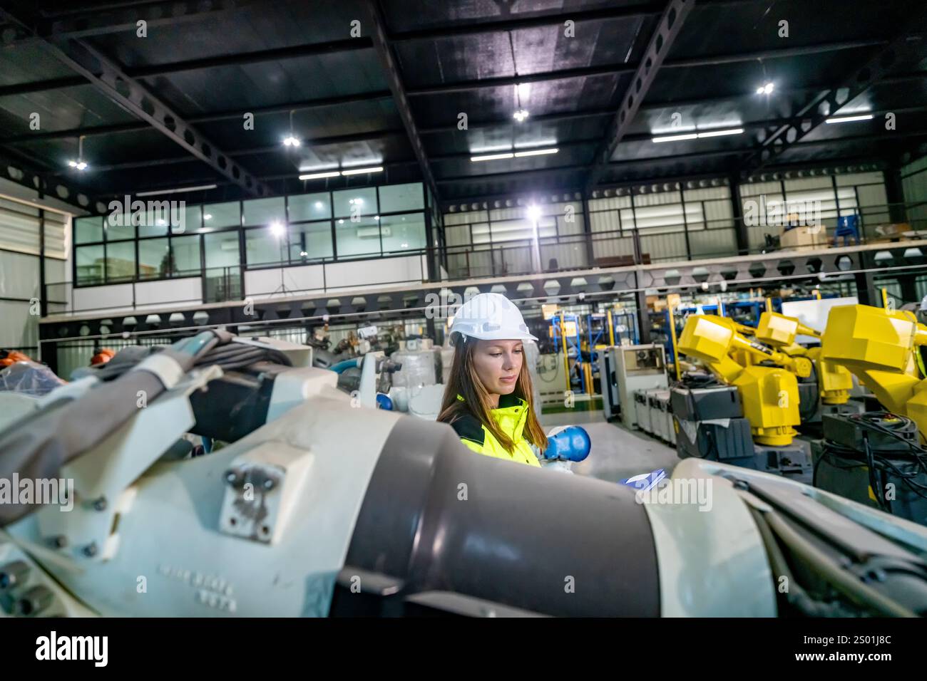 In a bustling manufacturing facility, an engineer wearing a hard hat ...