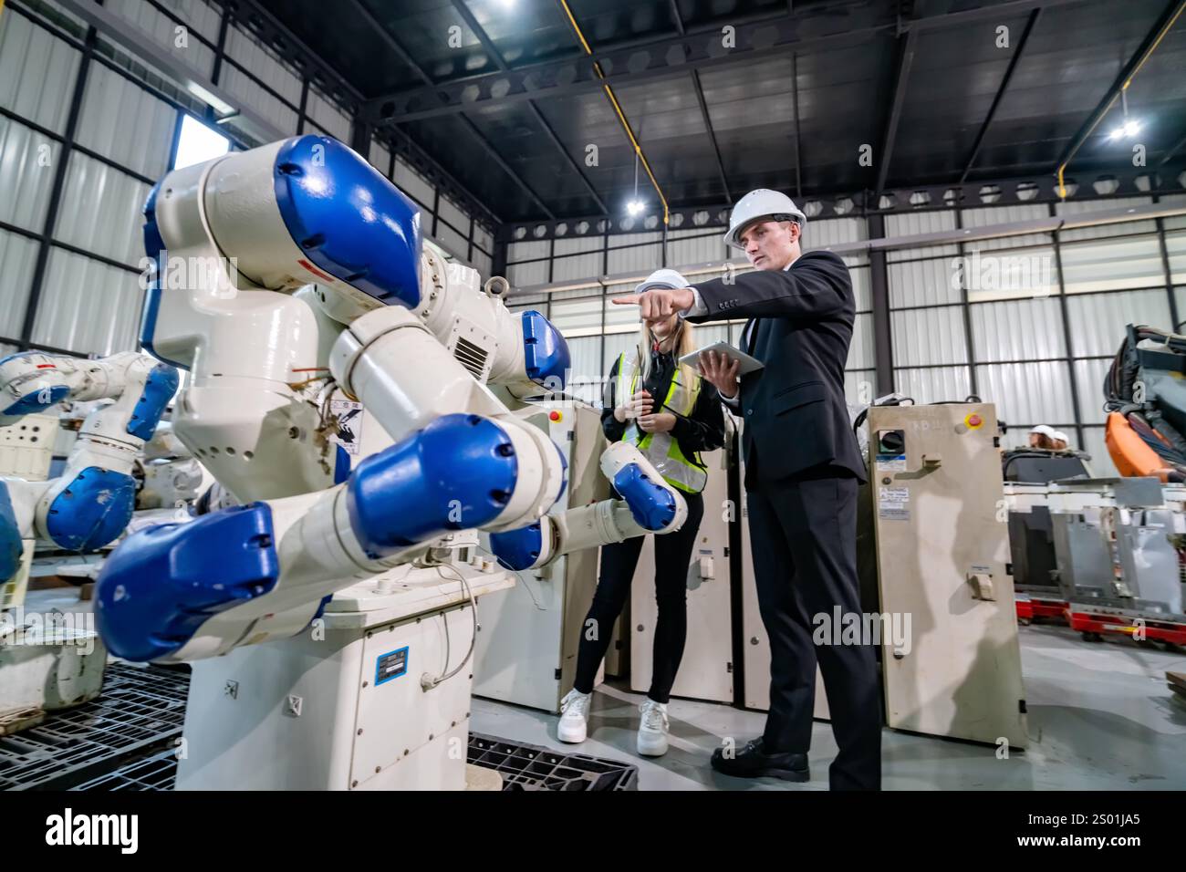 Two engineers, one male and one female, observe and discuss robotic ...